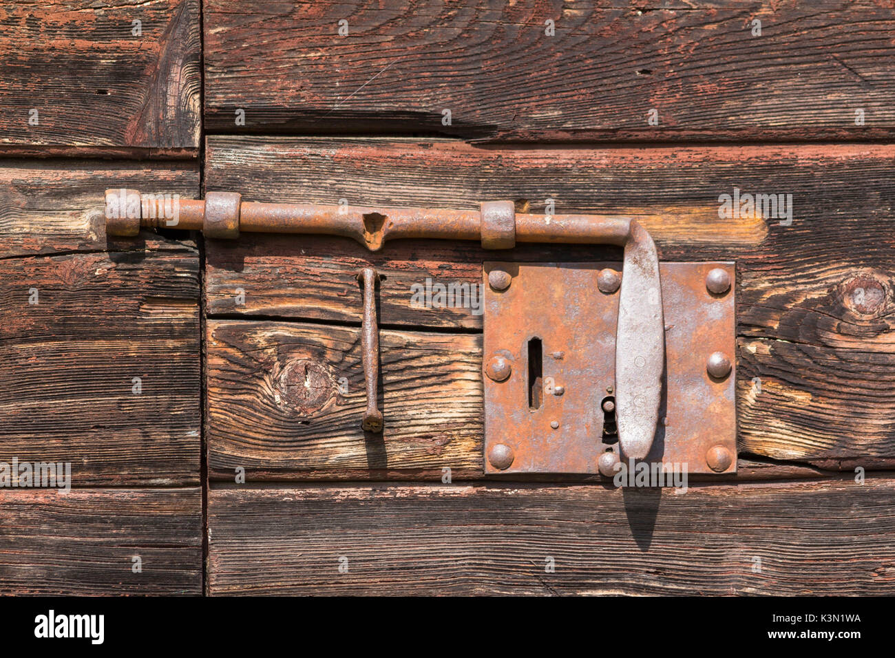 Old lock or latch on wooden door, typically used once in huts or barns ...