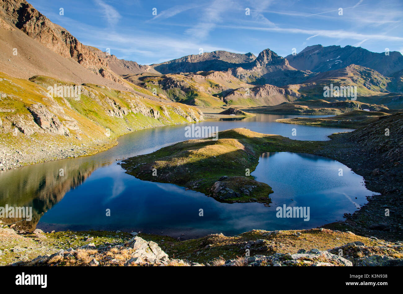 The calm surface of an alpine lake, under rocky ridges, in the early ...