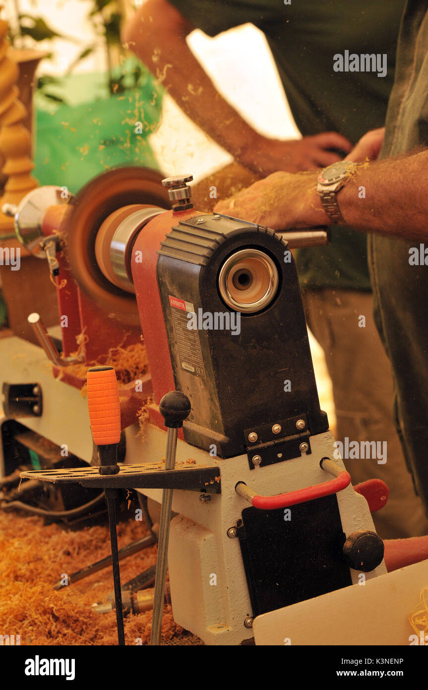 A man using a lathe wood turning carving and using chisels to form and ...