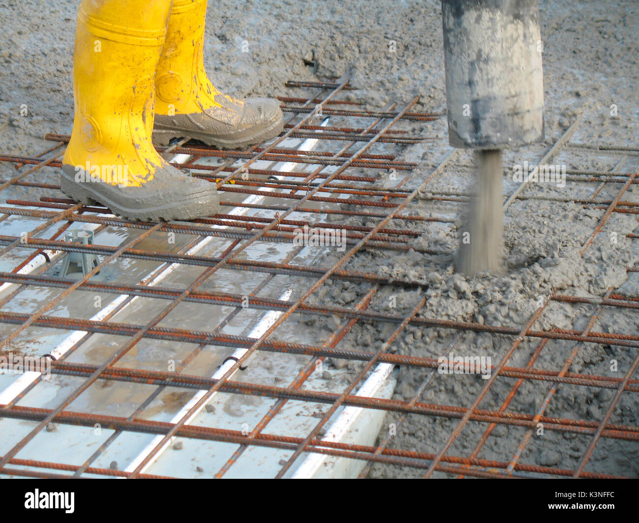 Construction worker pouring concrete on iron reinforcement for a ...