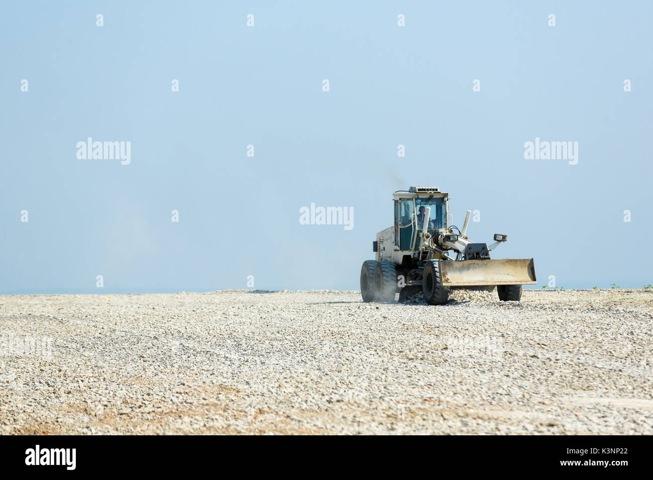 Industrial tractor grading surface prepearing it for further ...