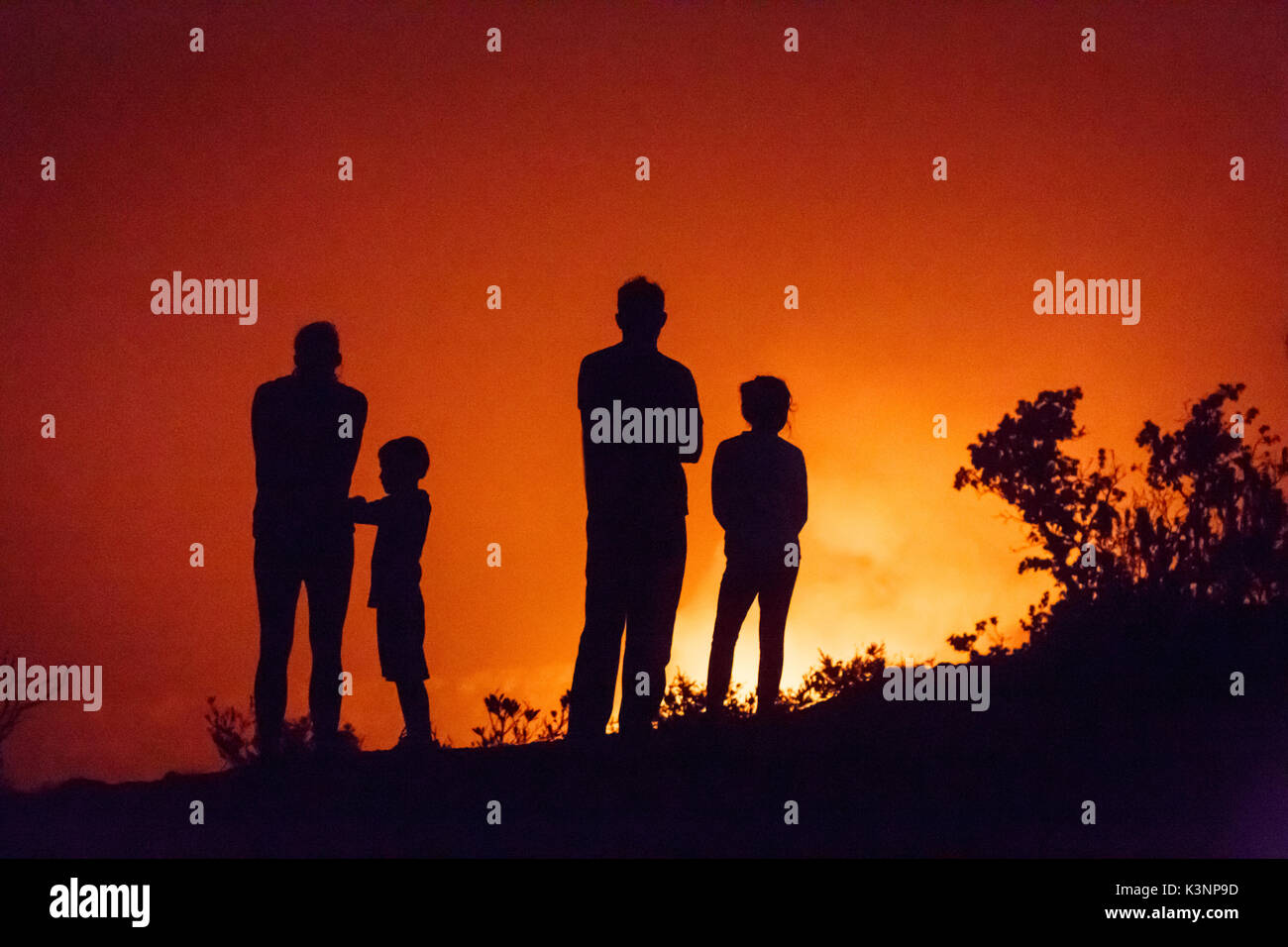 Silhouette of family standing on rim of an active glowing volcano Stock ...