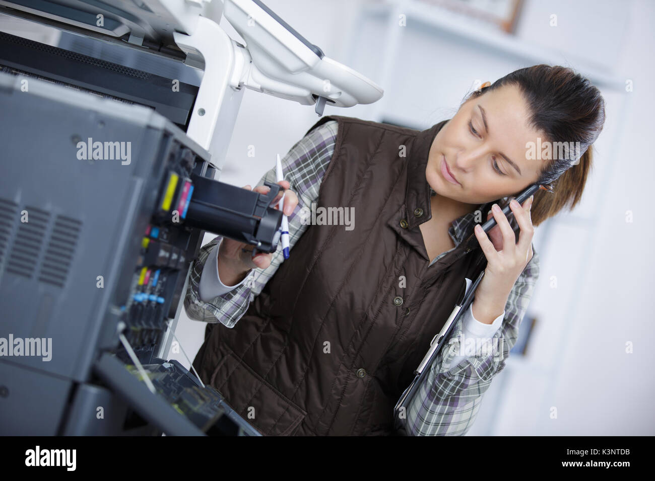young woman repairer on the phone standing next to printer Stock Photo ...