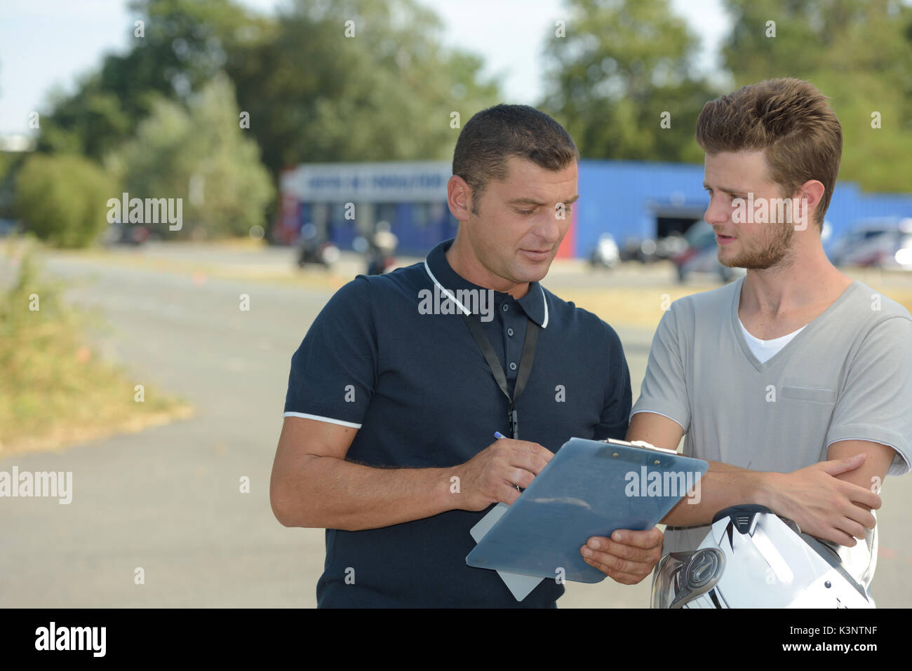 student and driving instructor writing on clipboard Stock Photo - Alamy