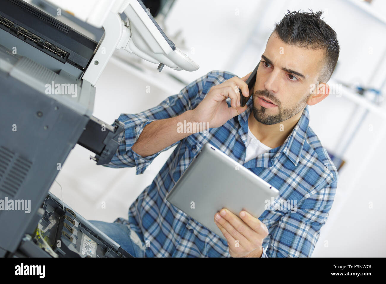 technician seeking help on the phone while repairing printer Stock ...