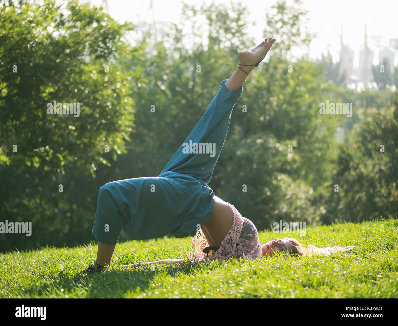 Portrait of young white woman runner stretching legs in the park. Green ...