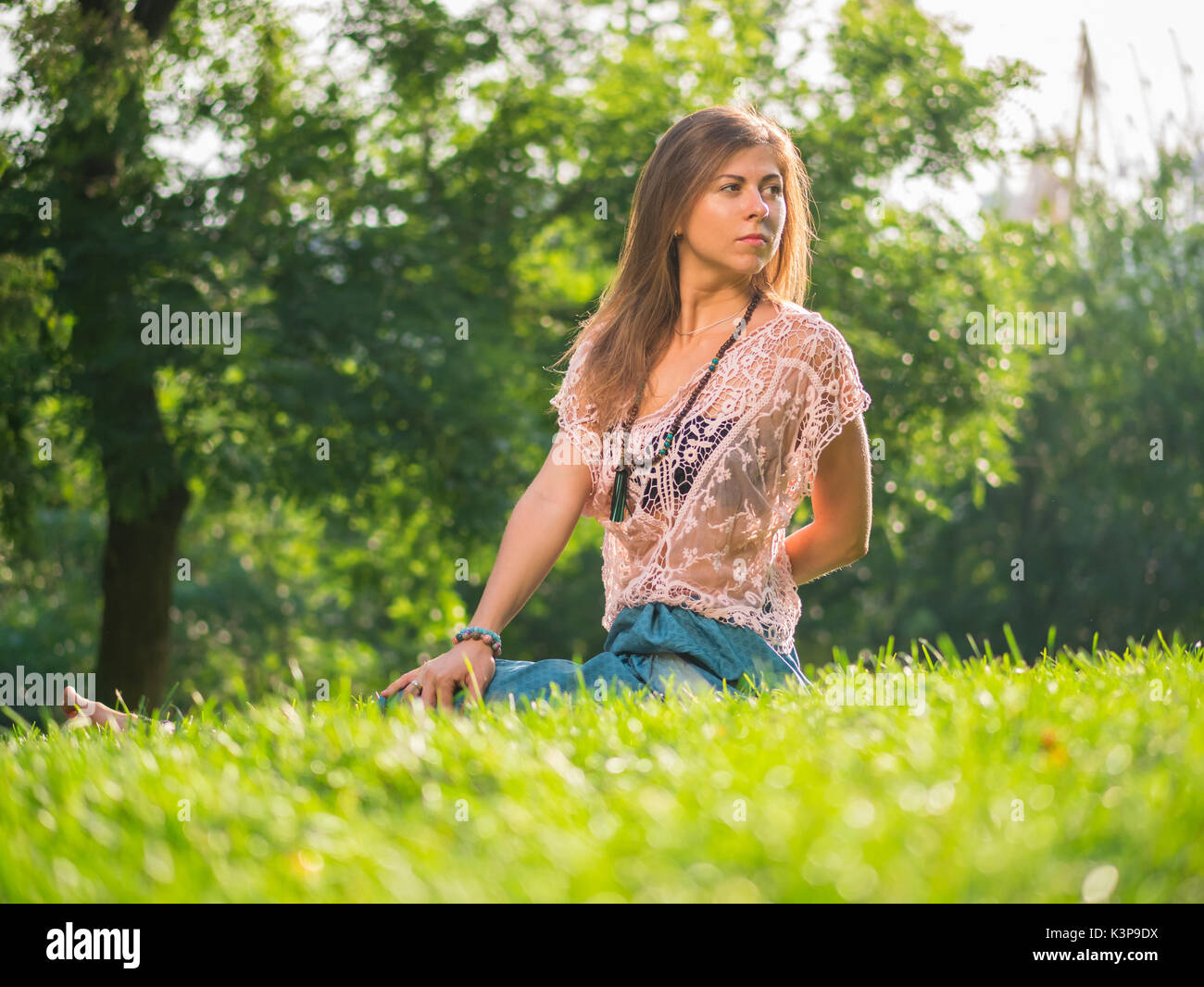 Portrait of young white woman runner stretching legs in the park. Green ...