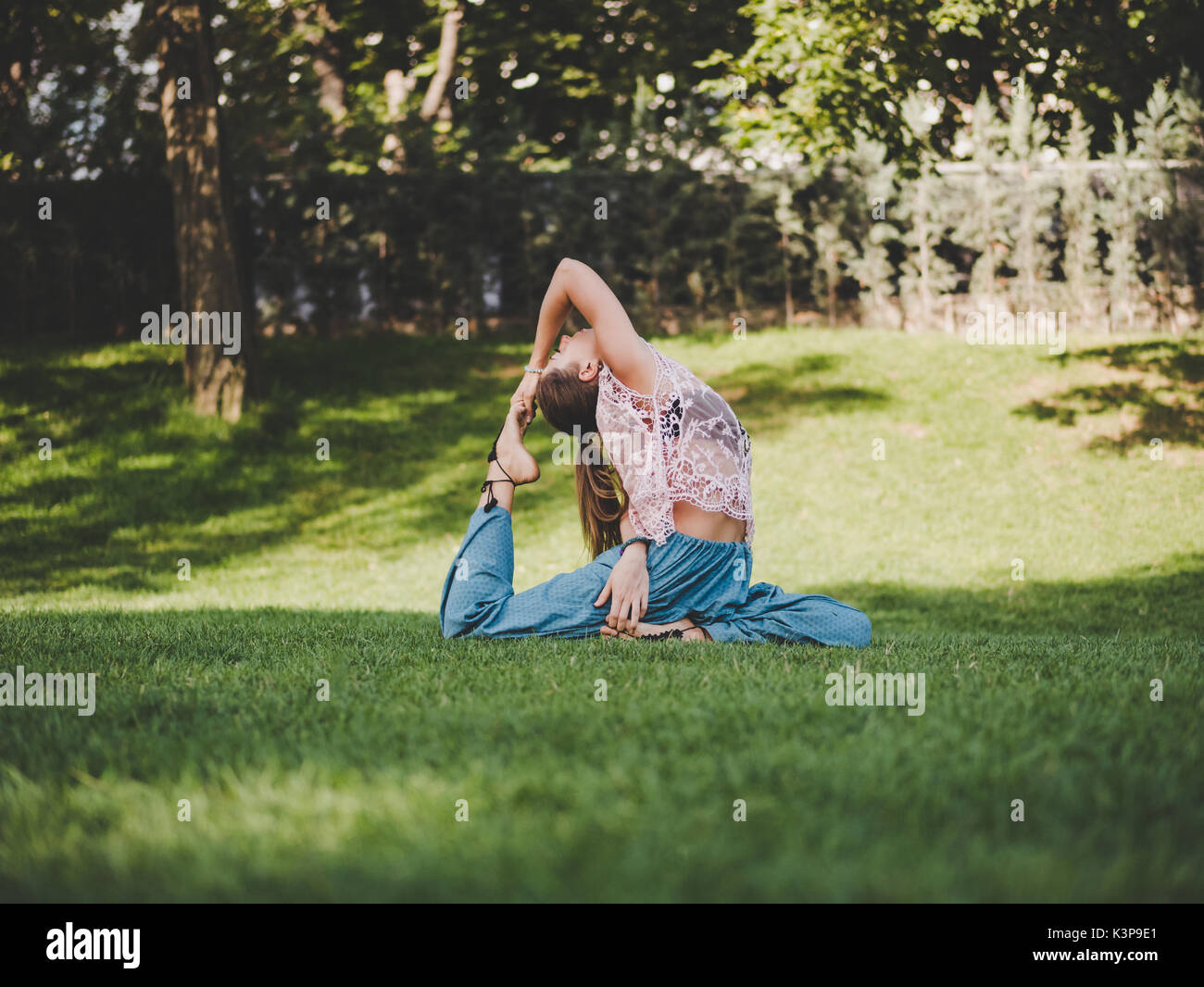 Portrait of young white woman runner stretching legs in the park. Green ...