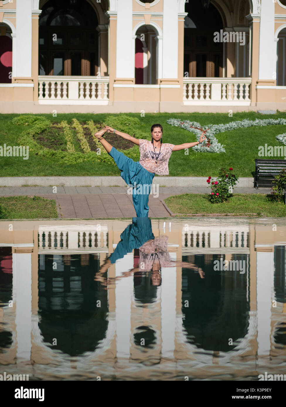 Reflection in the water of a sportive woman making stretching bent ...