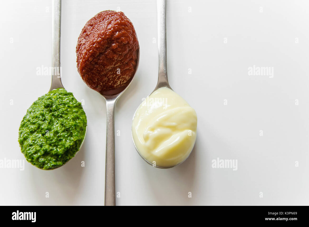 Three spoons with different condiments - mayonnaise, tomato sauce and ...
