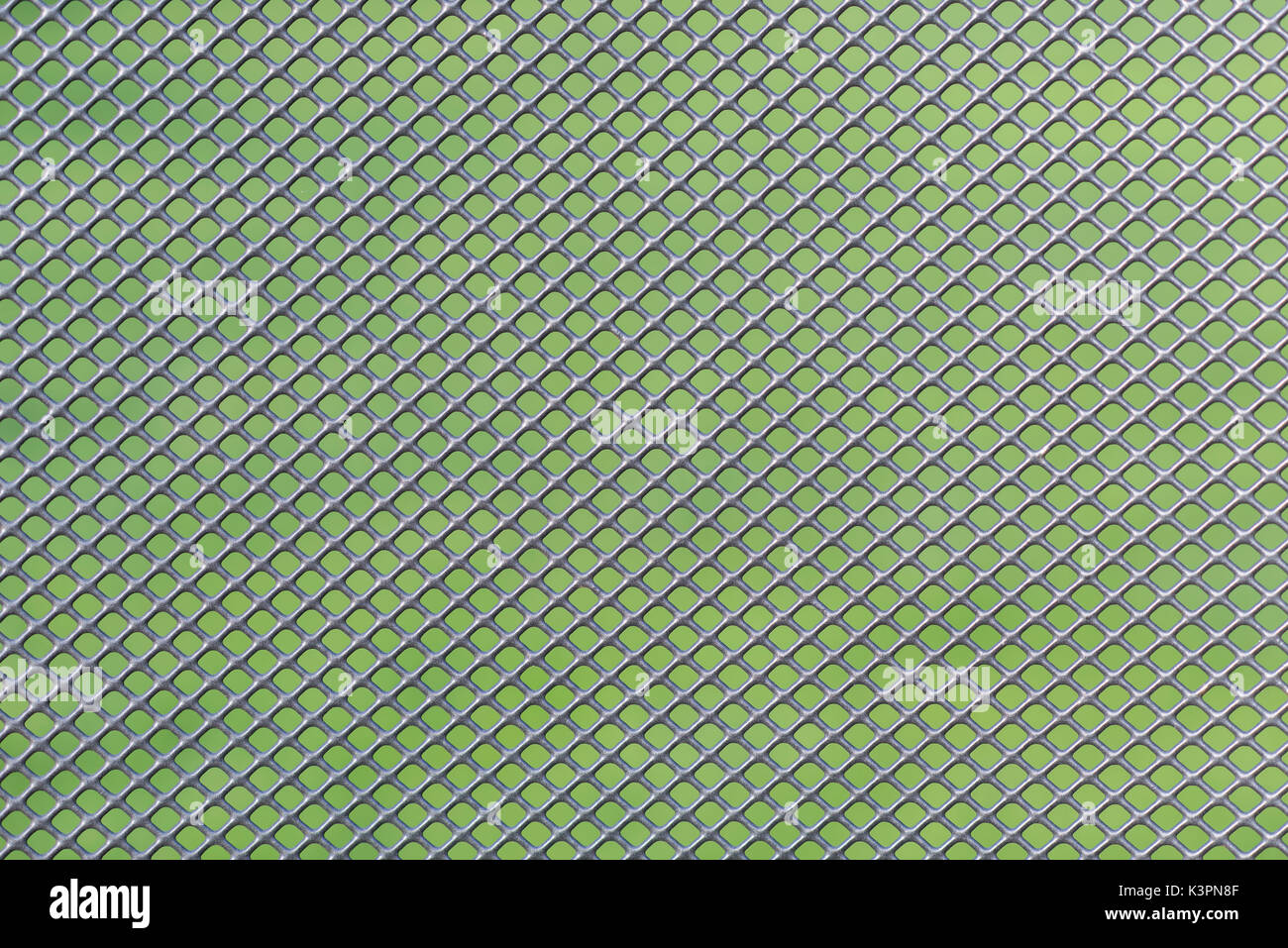 Grey metal wire mesh work against a green background as a background ...