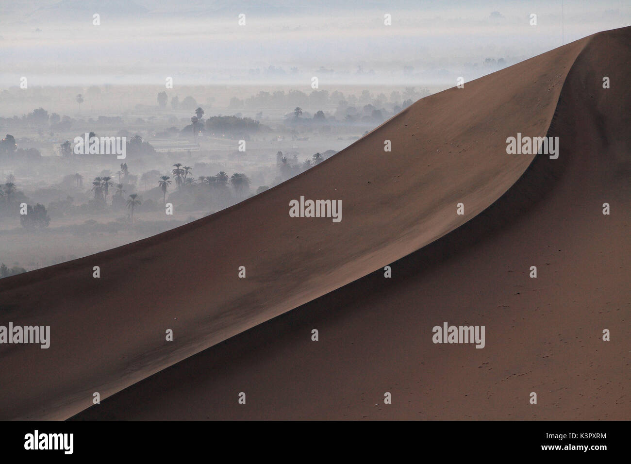 Dunes in the Peru desert and oasis wrapped in the fog in the distance ...