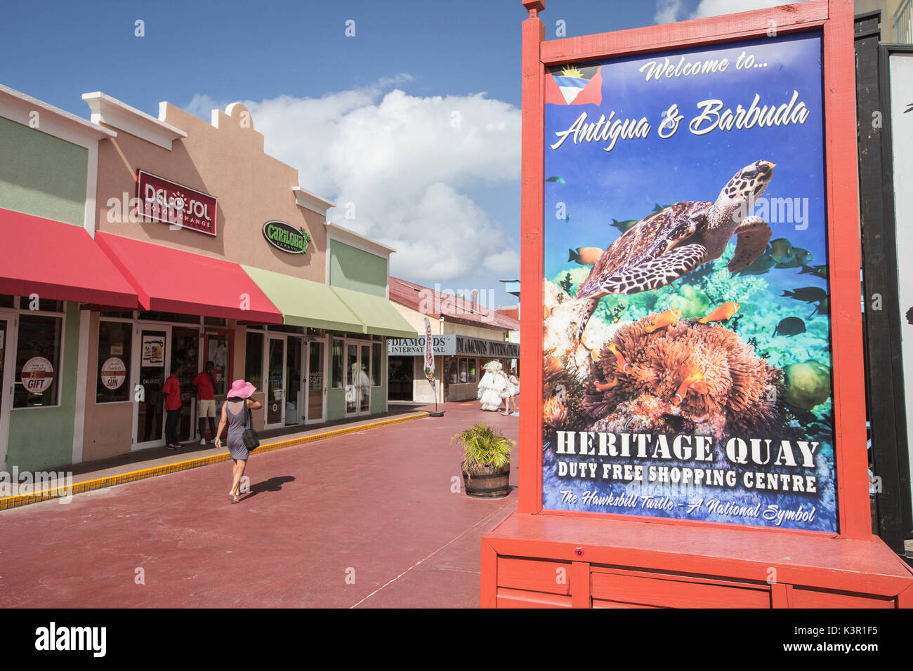 A tourist walks in a colorful road filled with shops Saint John's ...