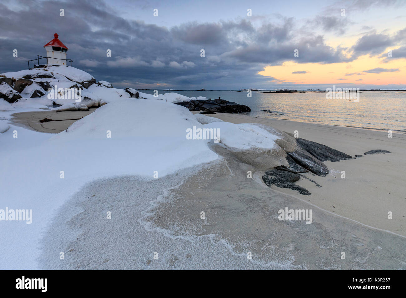 The blue arctic dusk on the lighthouse surrounded by snow and icy sand ...
