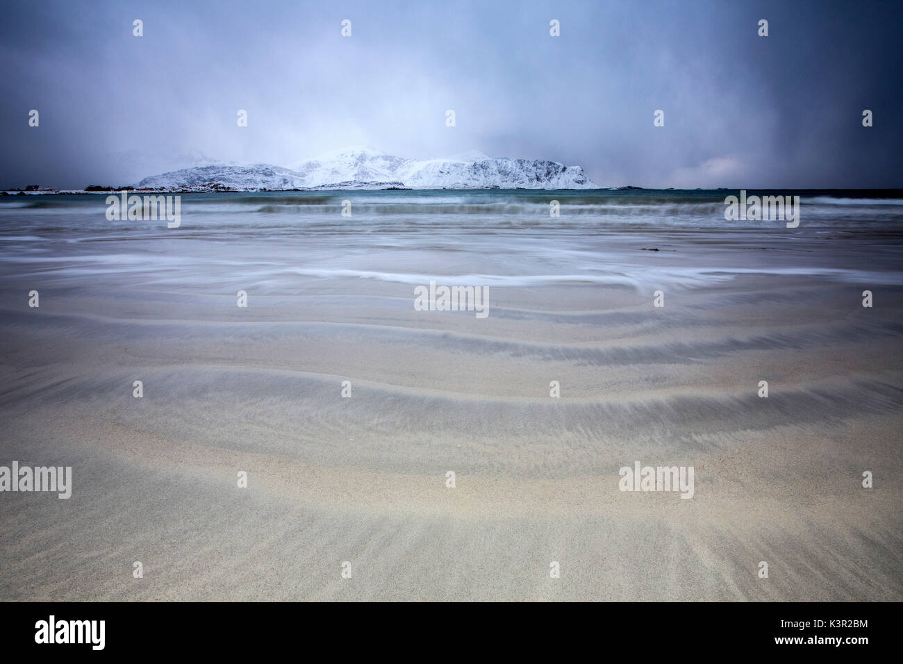 Waves of the icy sea on the beach in the background the snowy peaks ...