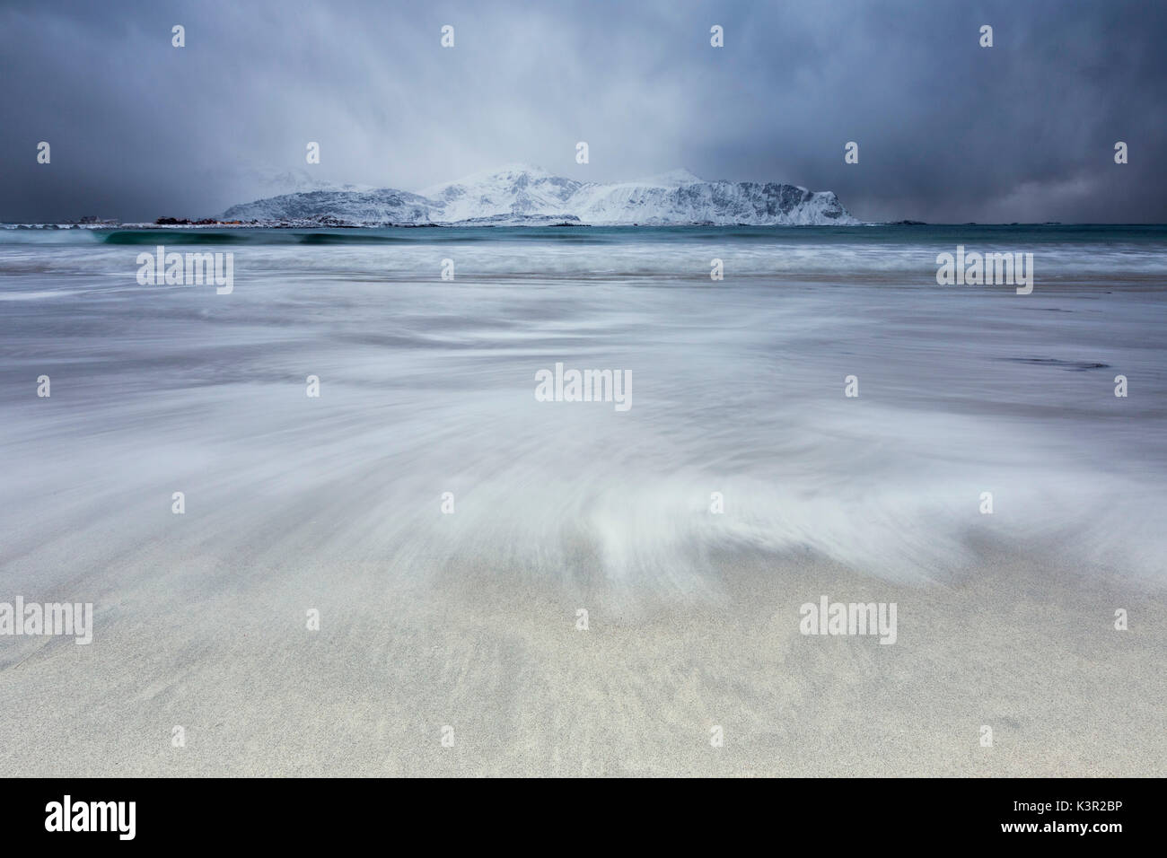 Waves of the icy sea on the beach in the background the snowy peaks ...