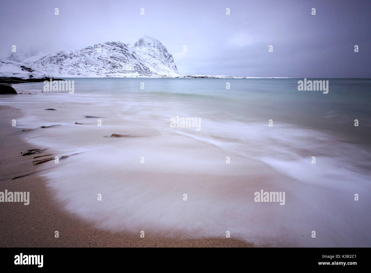 Waves of the icy sea on the beach in the background the snowy peaks ...