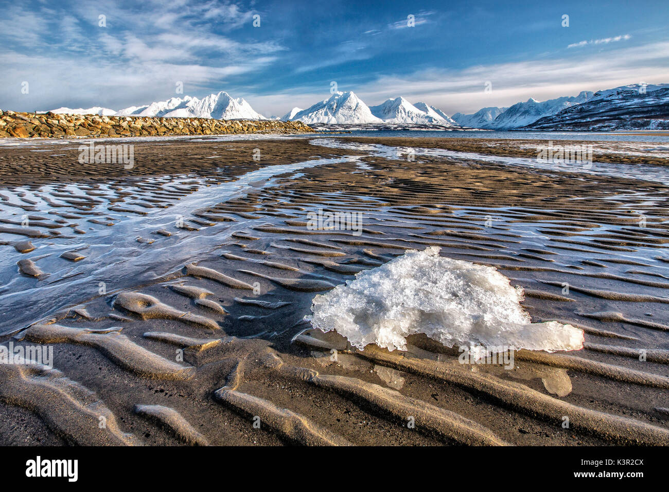 The icy sandy beach surrounding the snow capped mountains Breivikeidet ...
