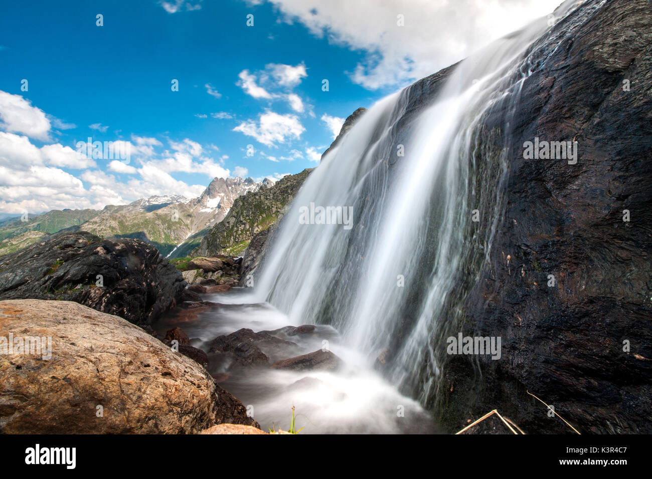 A waterfall with mountains in the background orobie alps hi-res stock ...