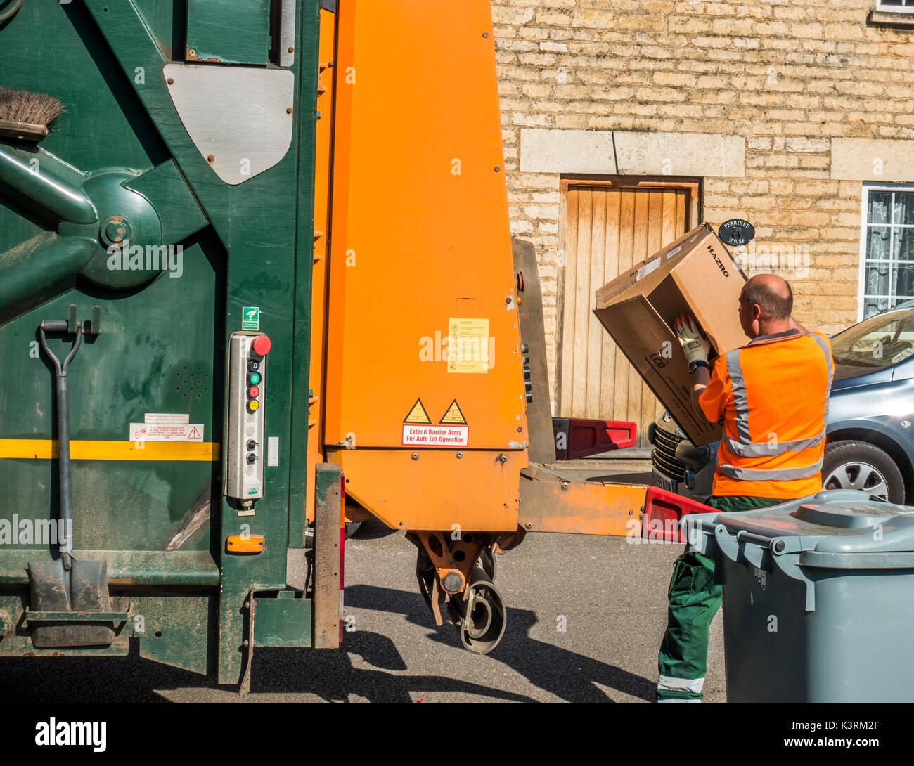 A council workman taking cardboard waste to the refuse lorry on a ...