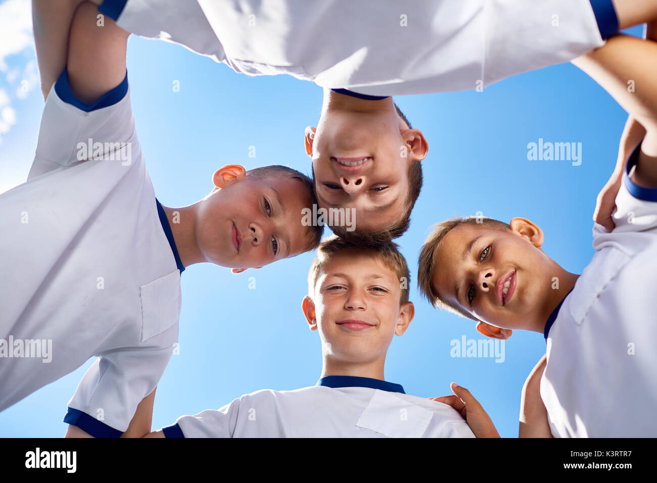 Low angle portrait of junior football team standing in circle and ...