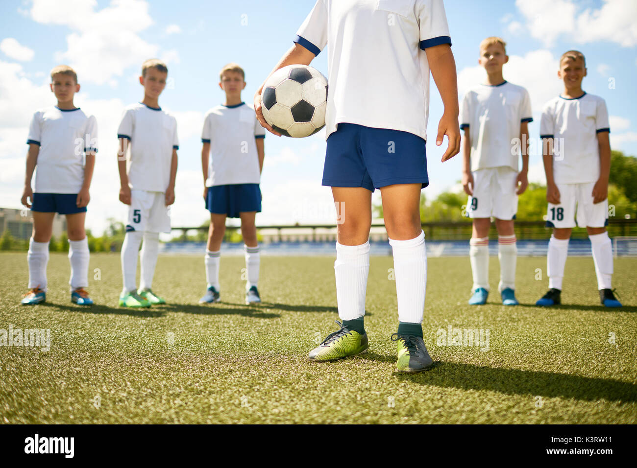 Low section portrait of football captain standing in center of field ...