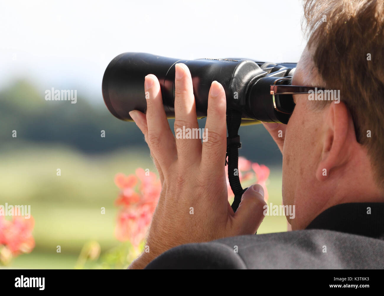 A spectator watches the race through binoculars on the 6th racing day ...
