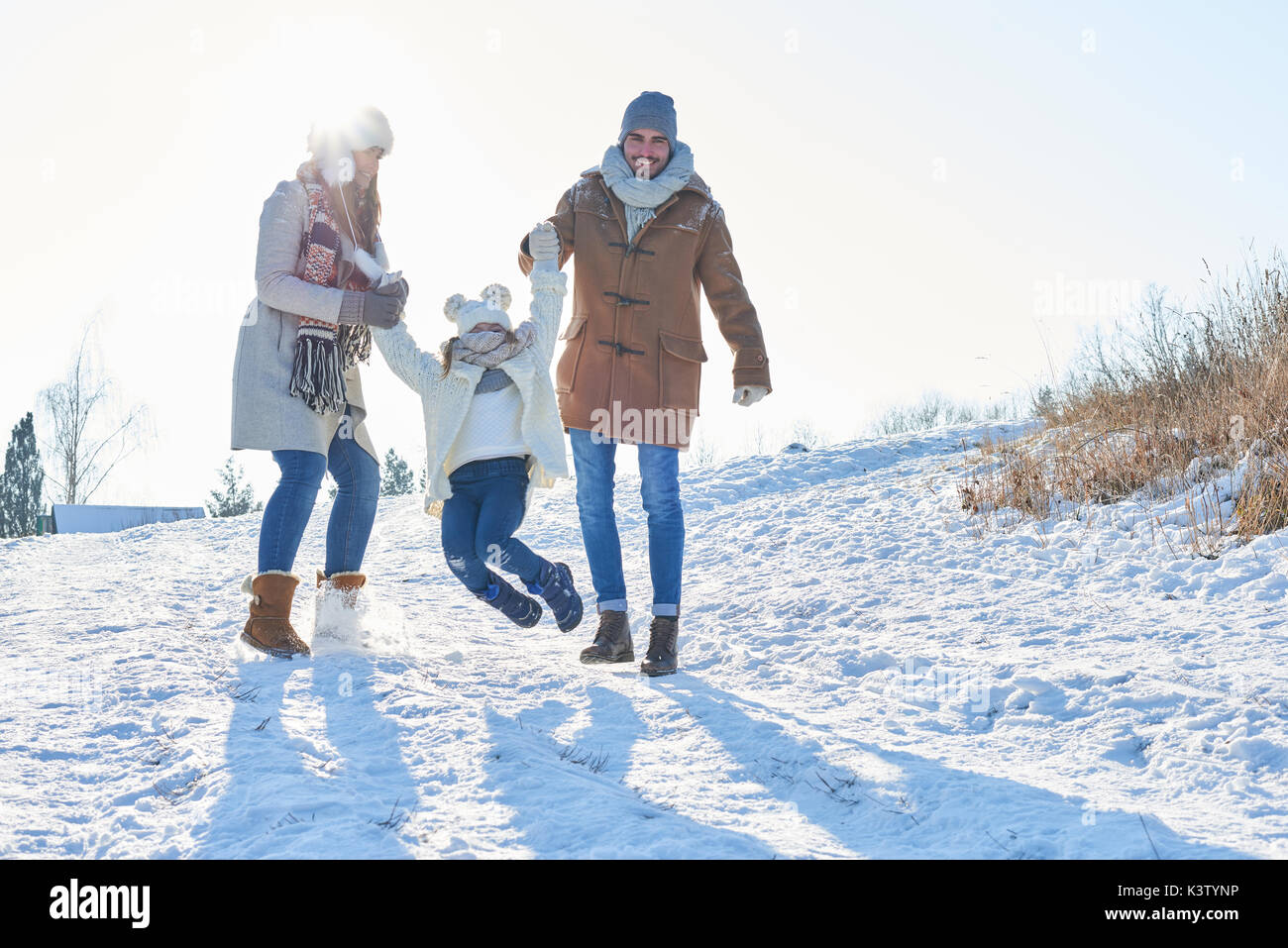 Family with child playing in the snow together in winter Stock Photo ...