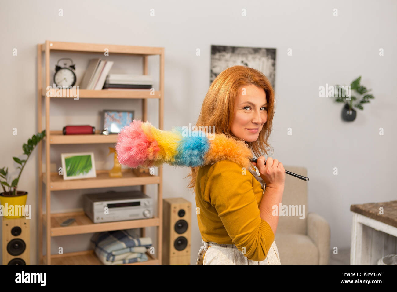 Attractive housewife holding whisk for dust on her shoulder Stock Photo ...
