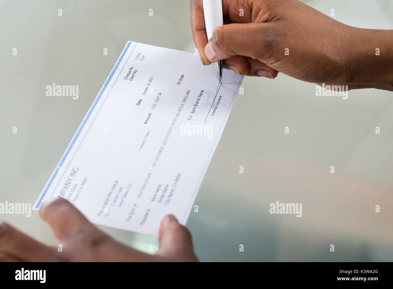Close-up Of A Person's Hand Signing Cheque Stock Photo - Alamy