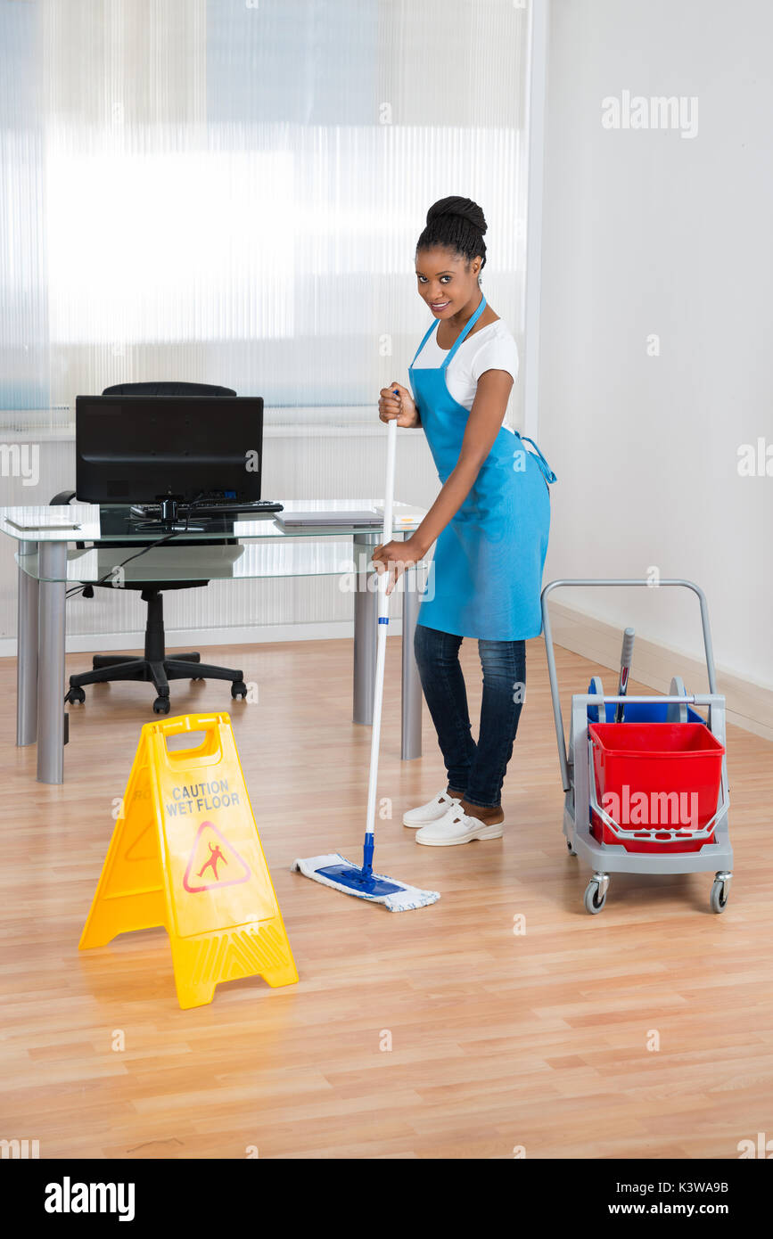 Smiling African Woman Cleaning Hardwood Floor In Office Stock Photo - Alamy