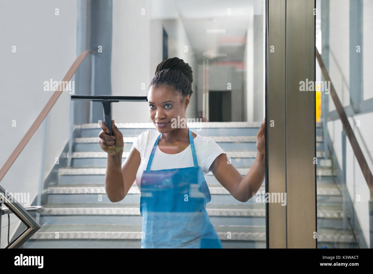 African Woman Cleaning Glass With Rubber Window Cleaner Stock Photo - Alamy