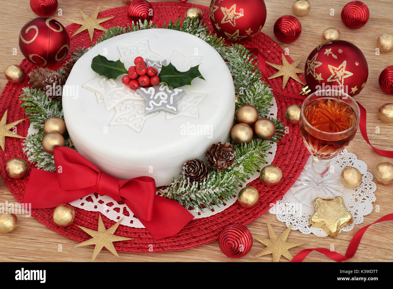 Iced christmas cake with glass of sherry, holly, fir, red and gold ...