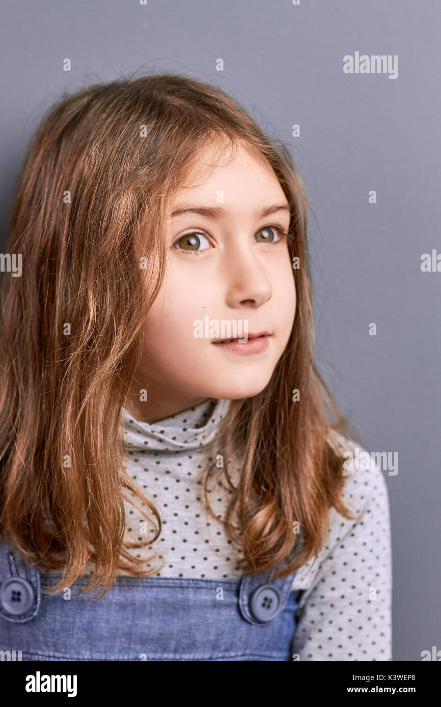 Portrait of thinking little girl indoor. Studio shot of pretty little ...