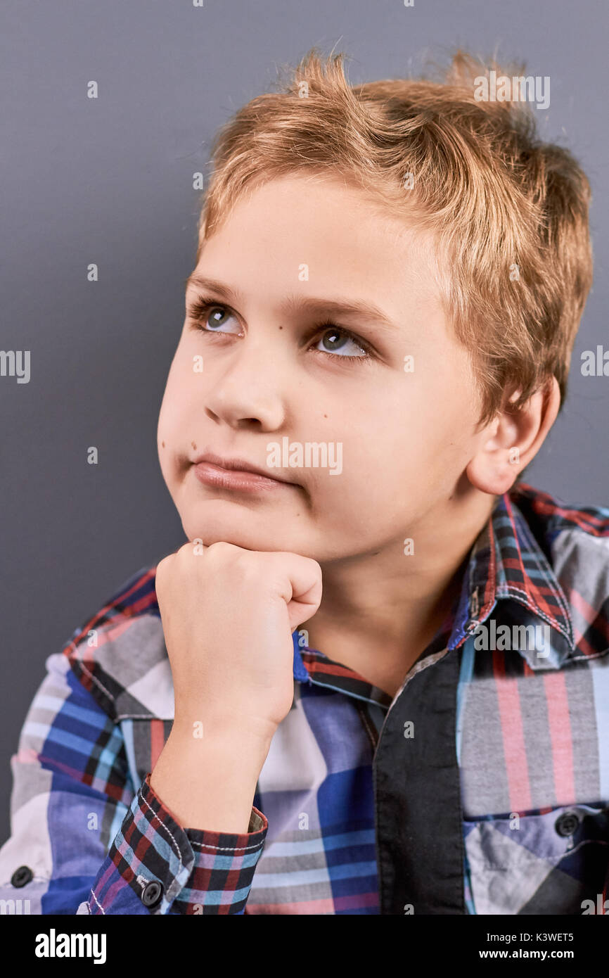 Portrait of little pensive boy. Handsome little boy holding his chin on ...