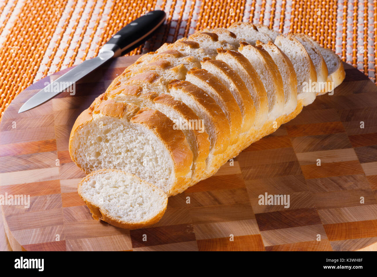 The white loaf cut on pieces on a beautiful wooden chopping board and a ...