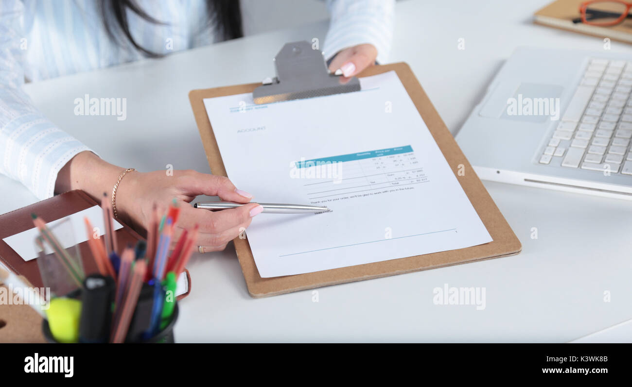 Business women sitting on desk and writing a paper Stock Photo - Alamy