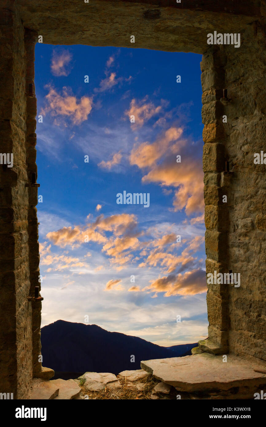 Evening sky with blue and red clouds visible through old ancient stone ...