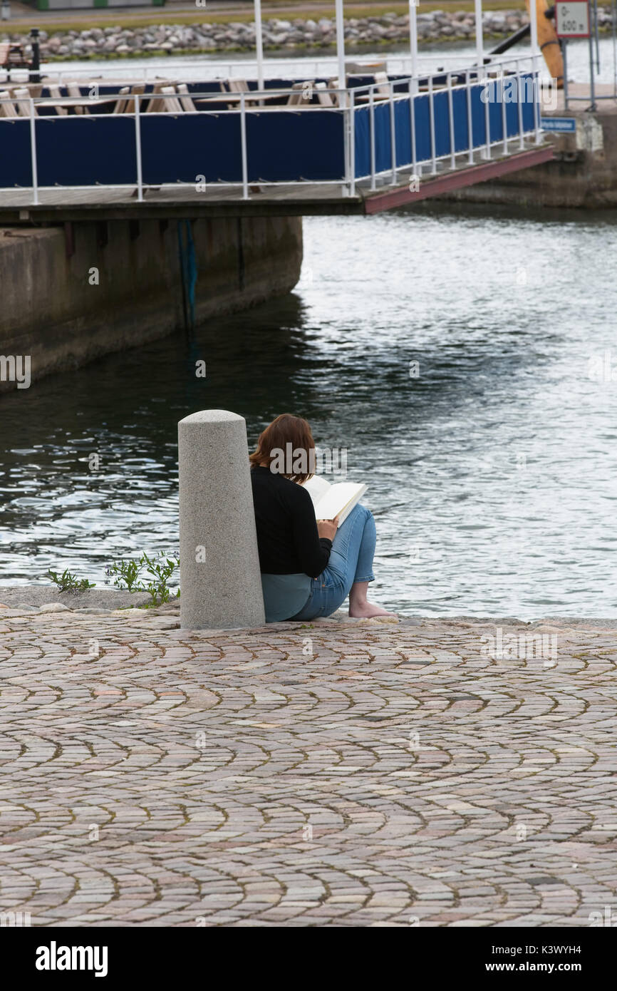 Woman reading a book by the water Stock Photo - Alamy