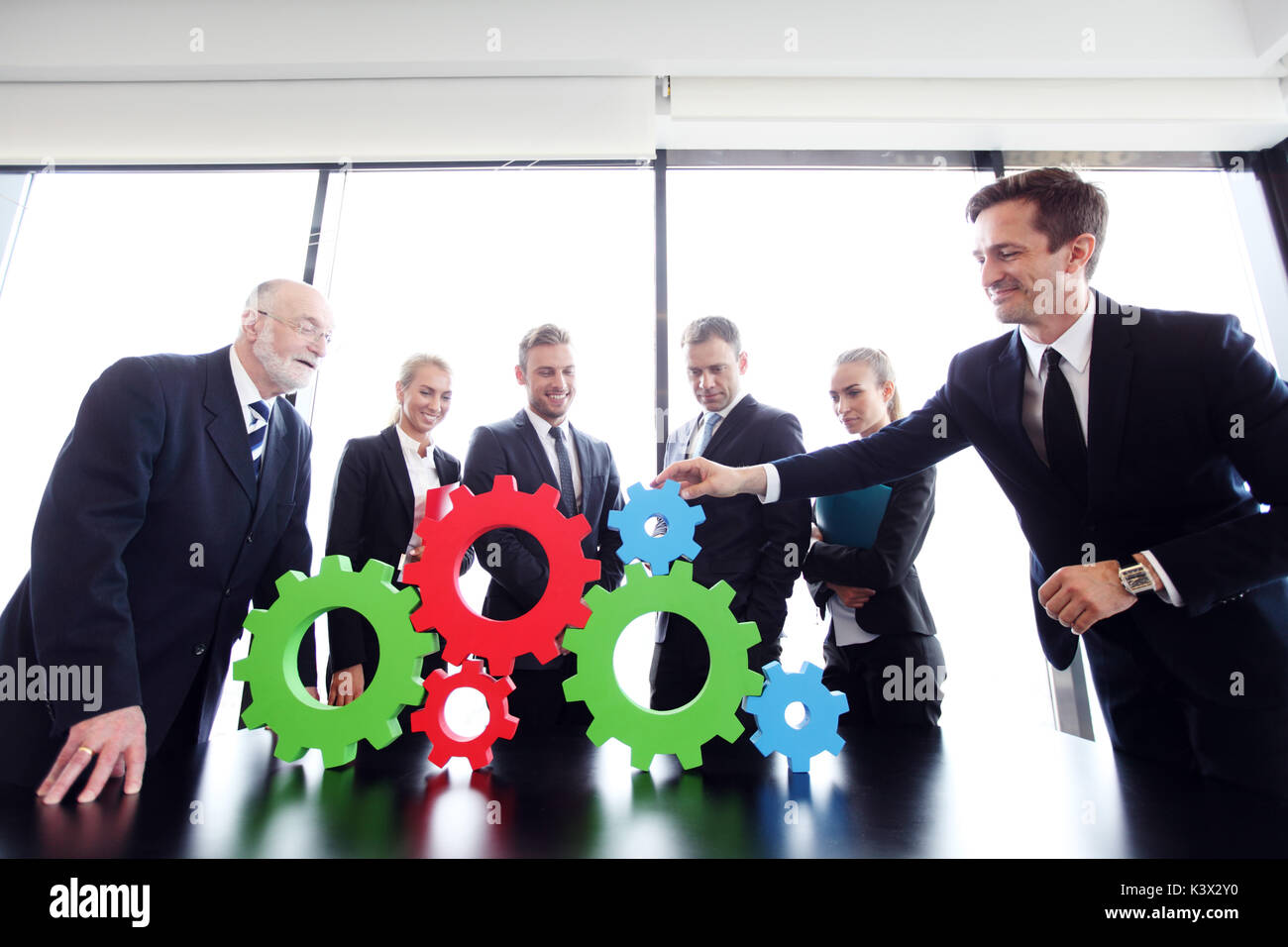 Business people assembling cogwheels, teamwork concept Stock Photo - Alamy