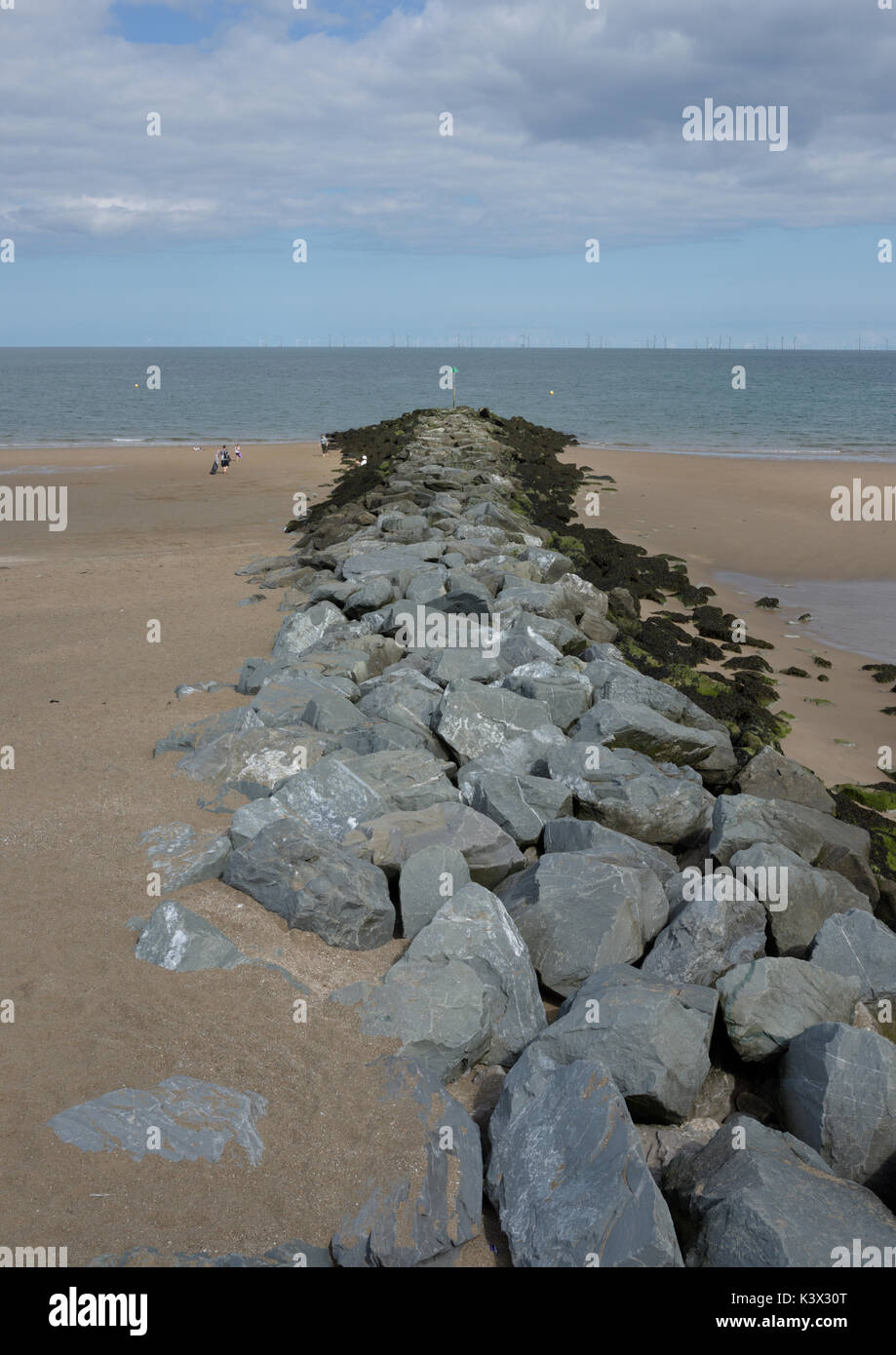 Rock boulder groyne with sand build up on porth eirias beach, part of ...