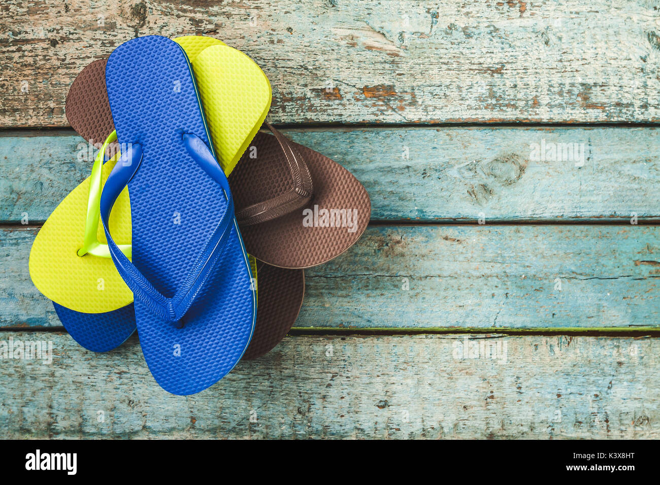 stack of several pairs of multi-colored rubber flip flops on a blue ...