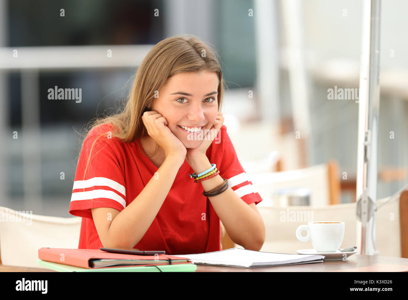 Happy student posing alone and looking at you sitting in a coffee shop ...