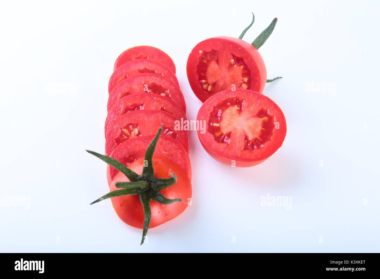 sliced fresh tomatoes with green leaves isolated on white background ...