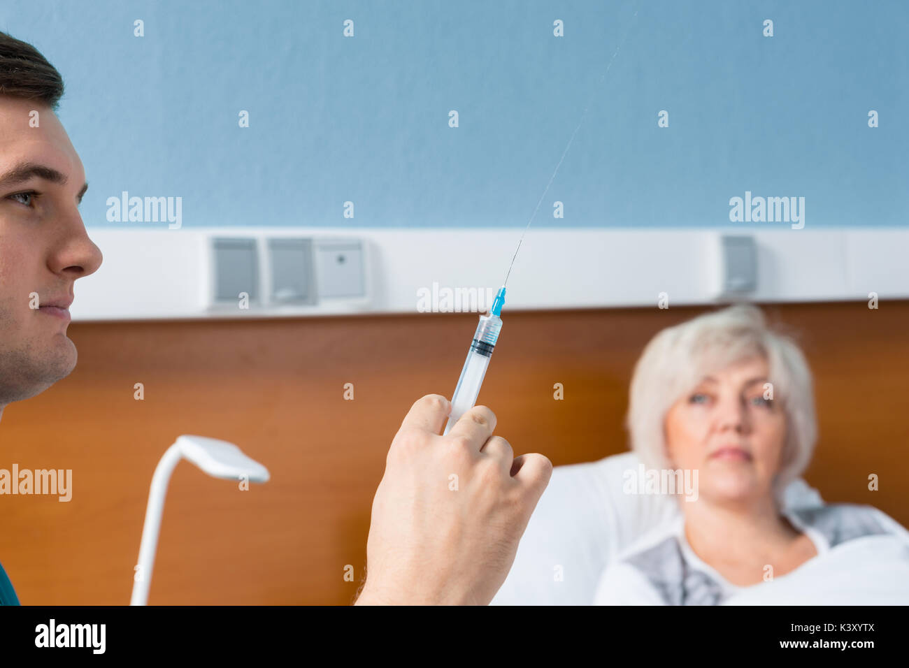 Male doctor in uniform is getting ready to do an injection to his ...