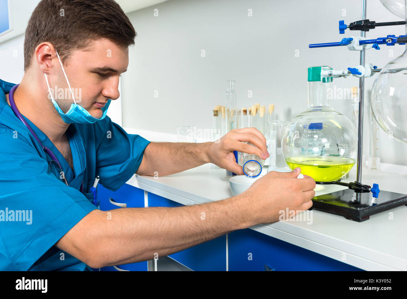 Young male scientist in uniform wearing a mask is working with ...