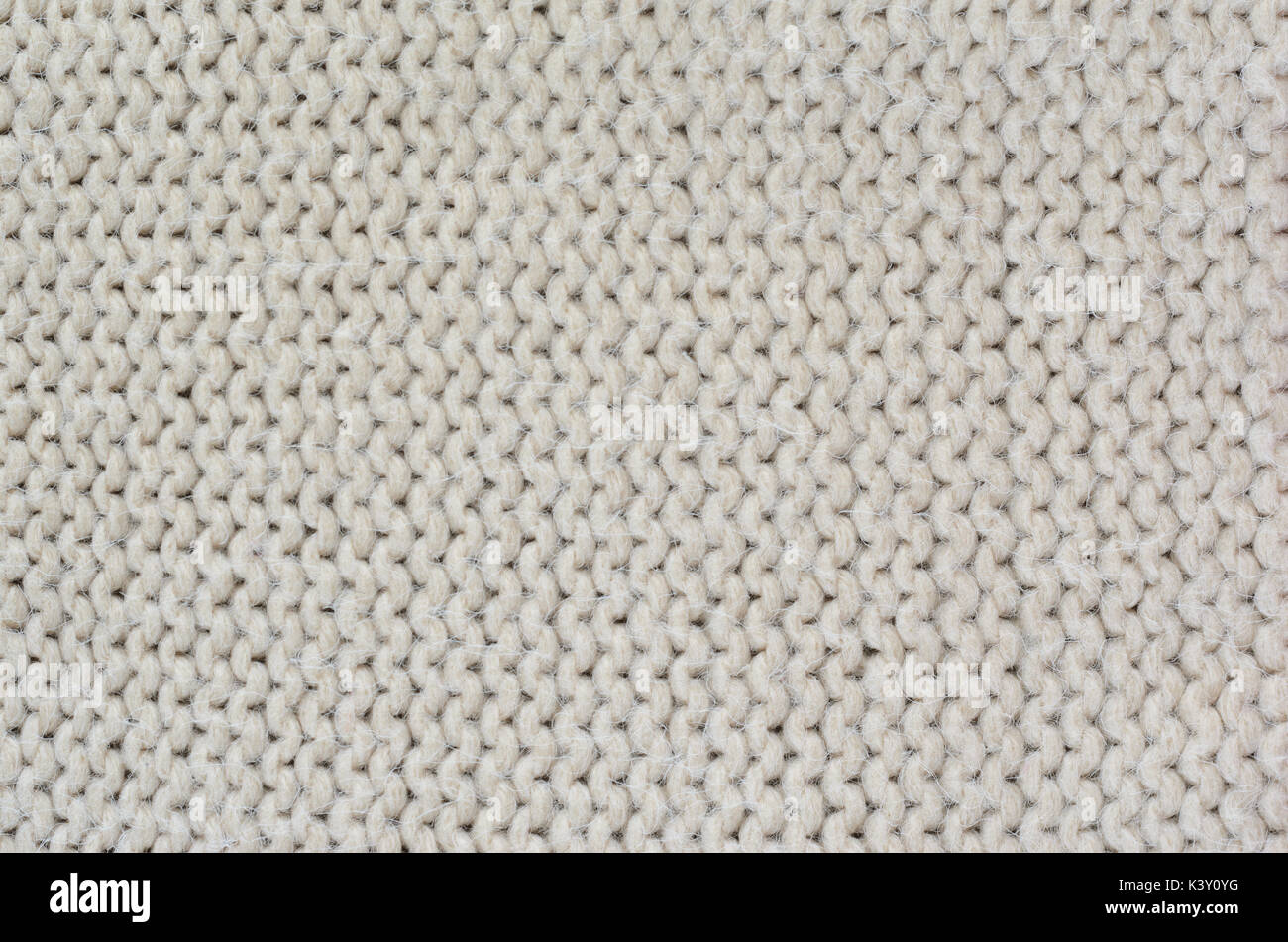 The texture of a thick knitted sweater beige close-up. Uniform knitting ...