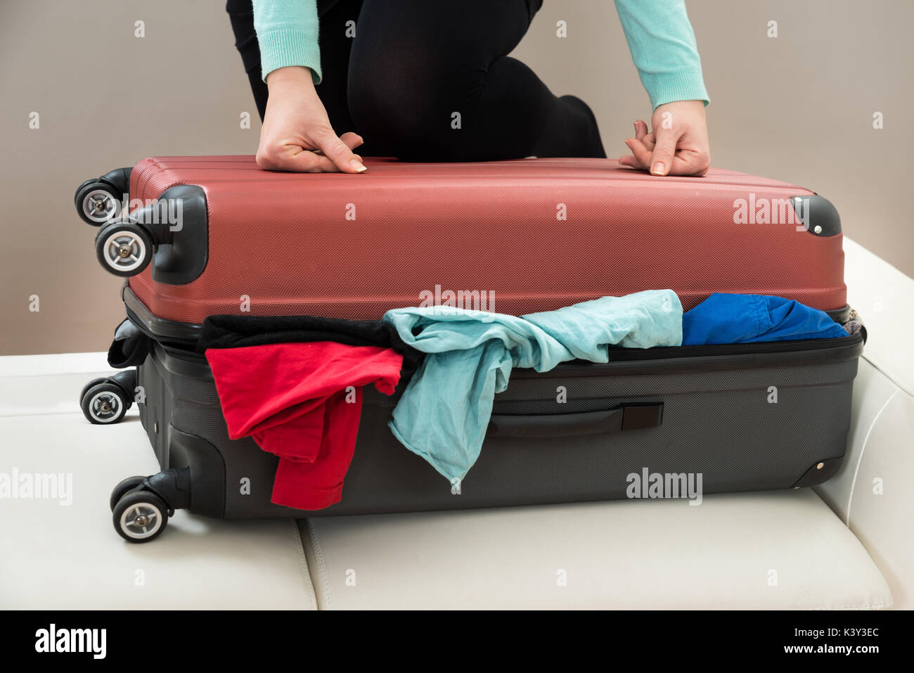 Close-up Of Woman Trying To Close Suitcase With Excess Of Clothes Stock ...