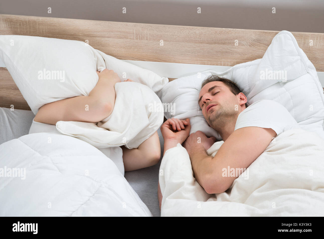 Wife Covering Ears From Cushion While Husband Snoring In Bedroom Stock ...