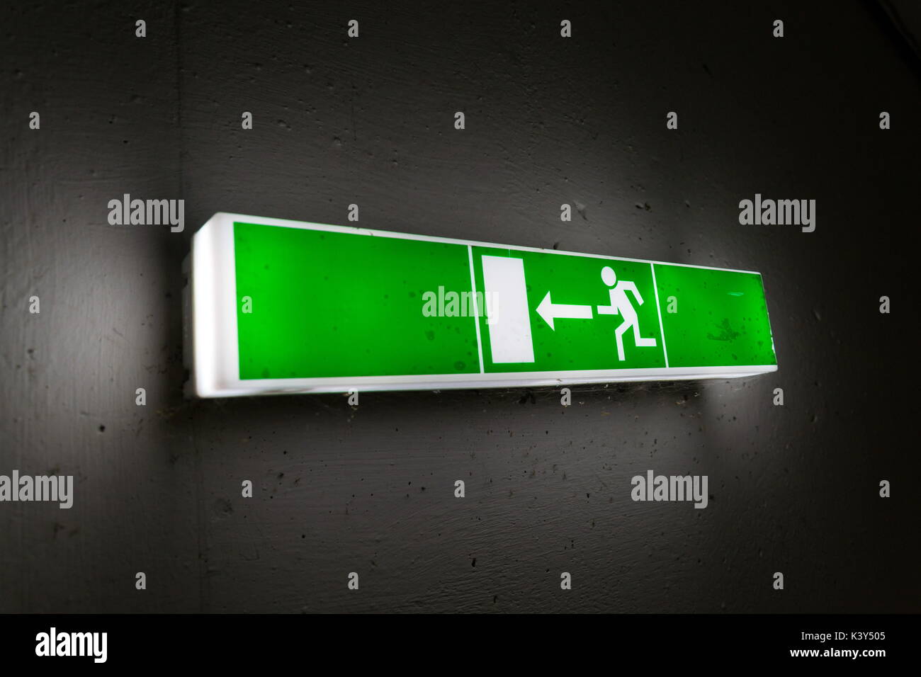 Green shining escape exit sign on white concrete wall Stock Photo - Alamy